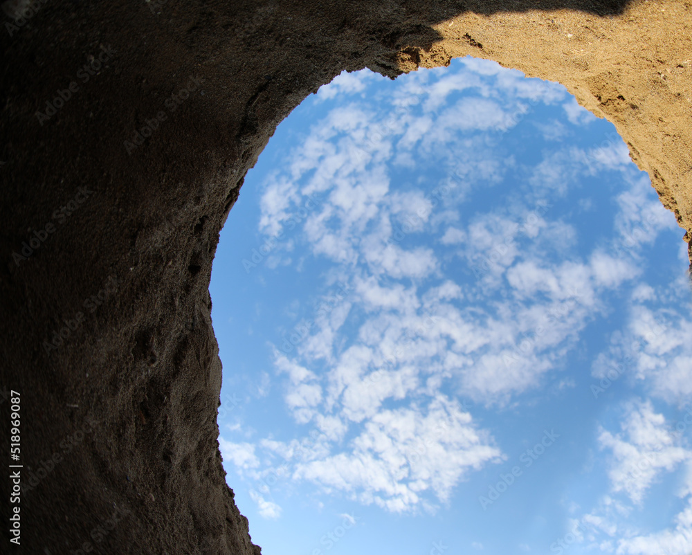 unusual view from inside a hole dug in the sand from which you can see ...
