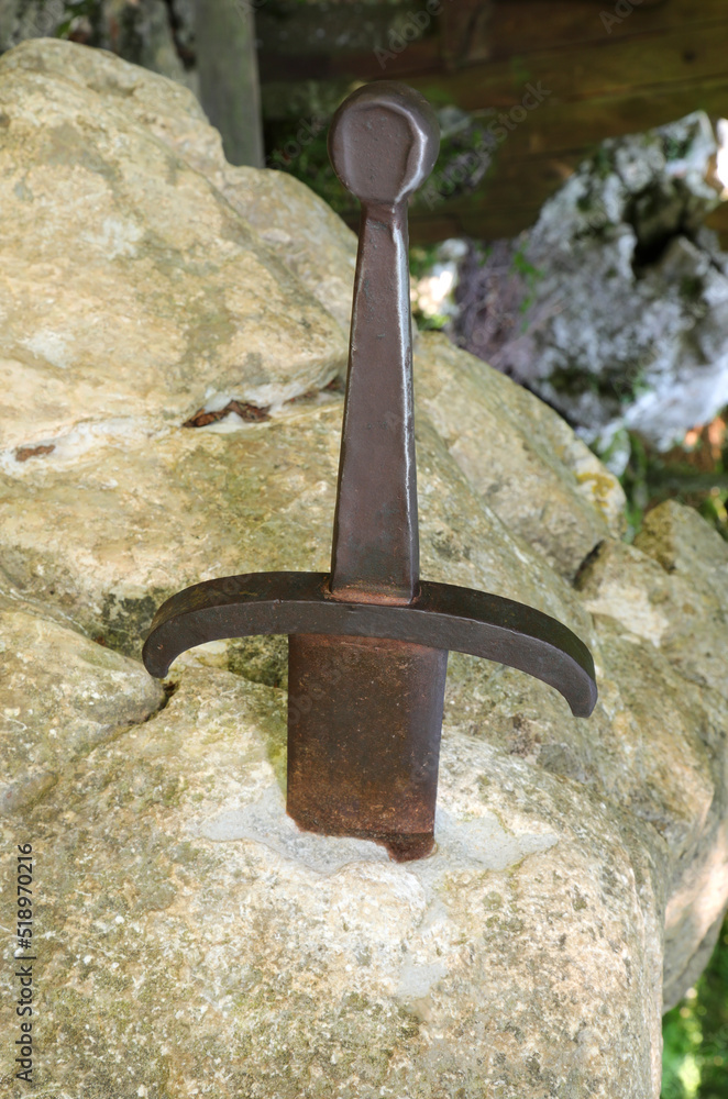 sword set in the stone in the middle of the forest of trees symbol of ...