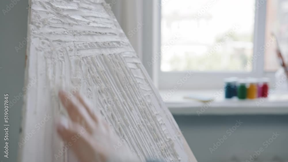 Close-up female dirty hand in white paint smears sticky plaster with ...