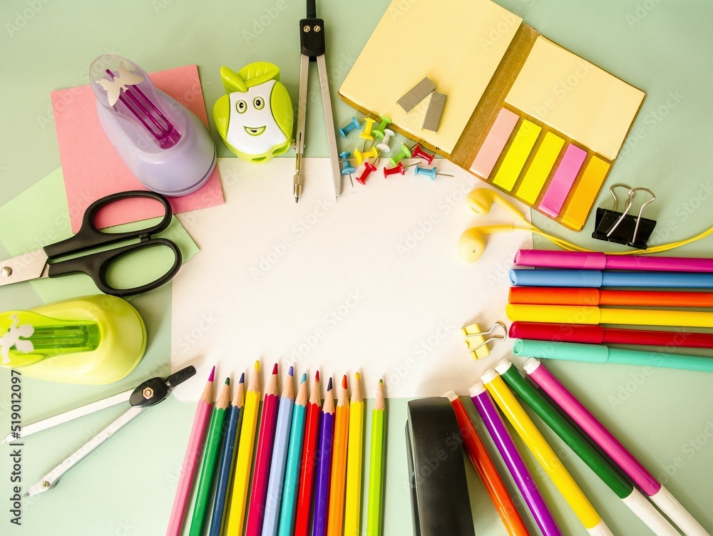 School supplies lie on a green background in a circle, colored pencils ...