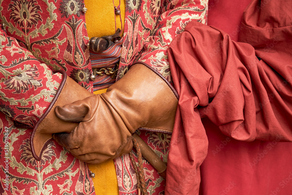 Man and woman hands an ornate vintage robe with retro weapons behind an ...