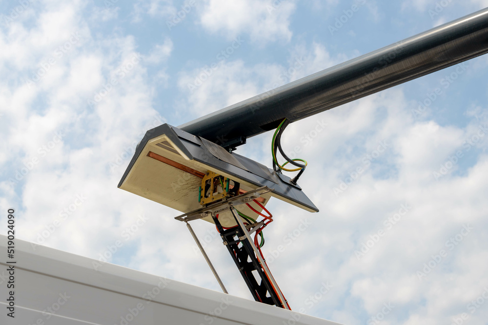 Pantograph of a city bus connecting on electric line with blue sky as ...
