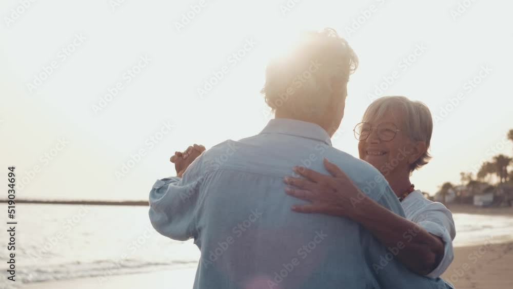 Couple of old mature people dancing together and having fun on the sand ...