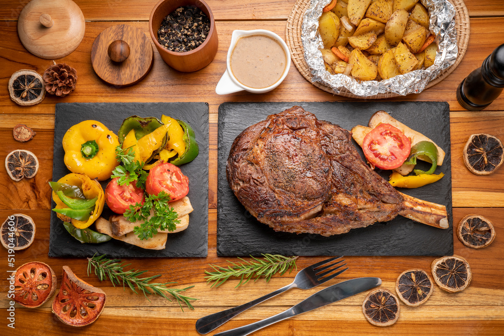 Foto Stock Grilled tomahawk ribeye steak in black stone plate on wooden ...