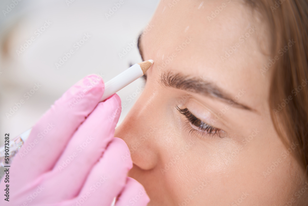 Lady between eyebrows is schematically marked with pencil for procedure ...