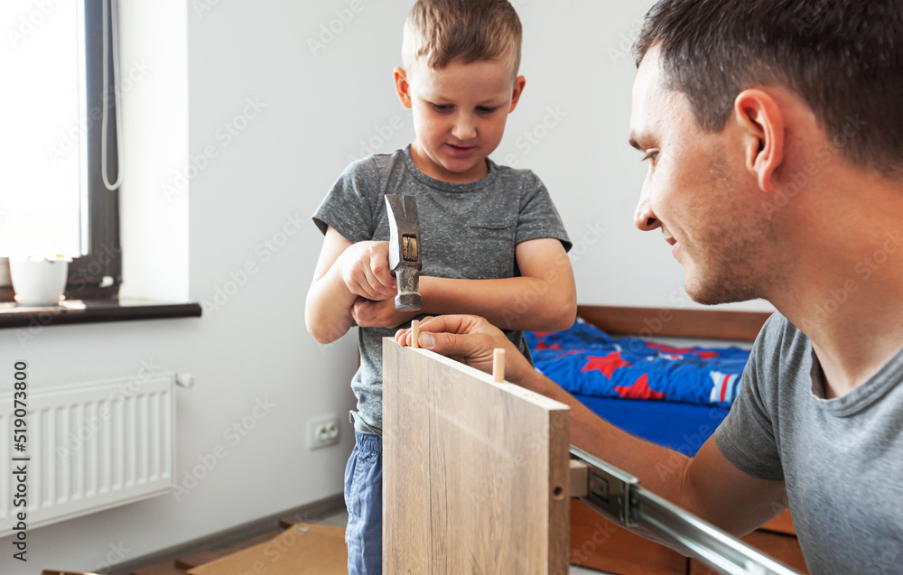 Father and son assembling the desk together and father teaches his son ...