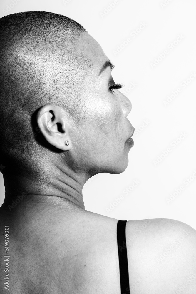 Abstract portrait. Woman standing back to camera with shaved head in ...