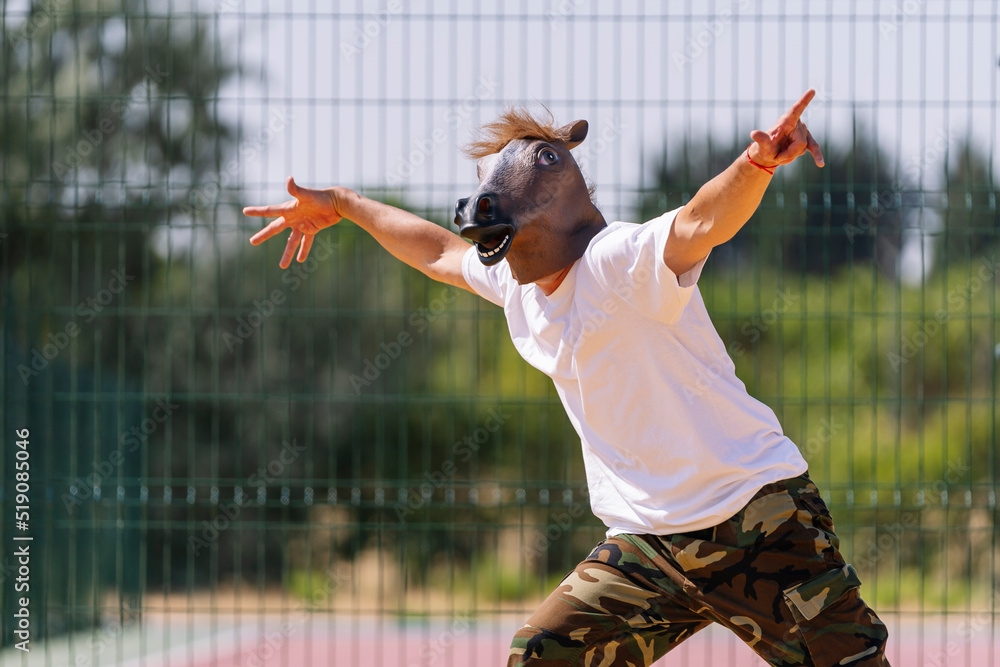 Man wearing animal mask dancing with arms outstretched on sunny day ...