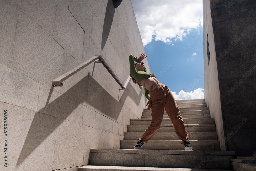 Young and attractive woman dancing freestyle dance in front of an urban ...