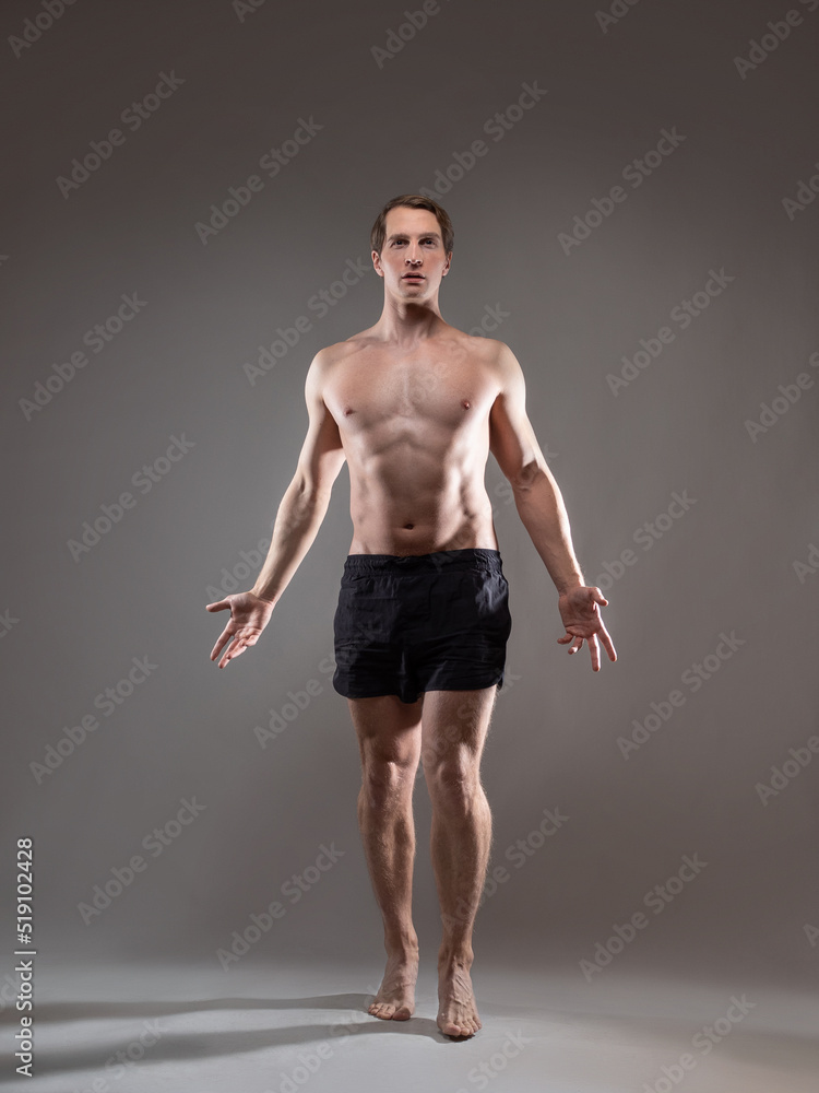 Muscular man in an artistic pose, portrait on a gray background. An ...