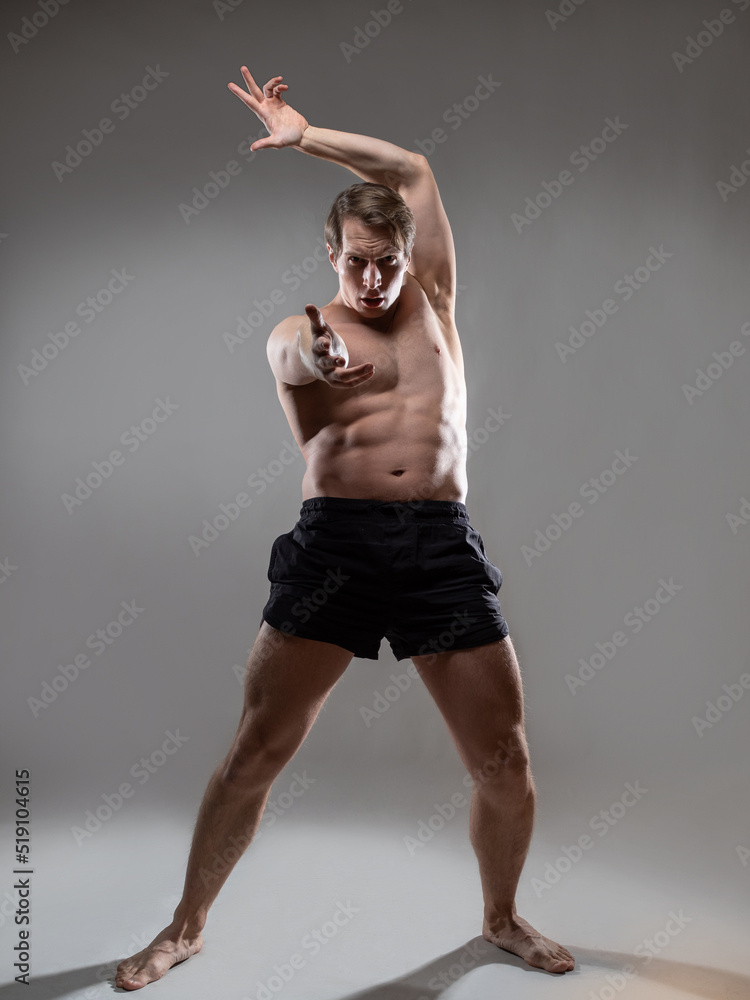Muscular man in an artistic pose, portrait on a gray background. An ...