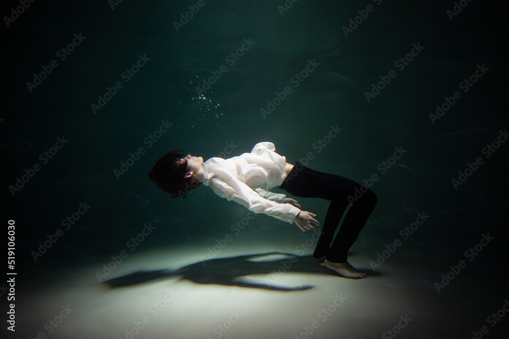 Beautiful underwater shooting, guy in white shirt and pants has fallen ...