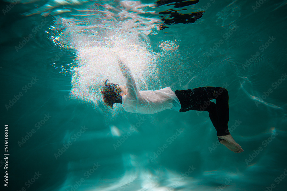 Beautiful underwater shooting, guy in white shirt and pants has fallen ...