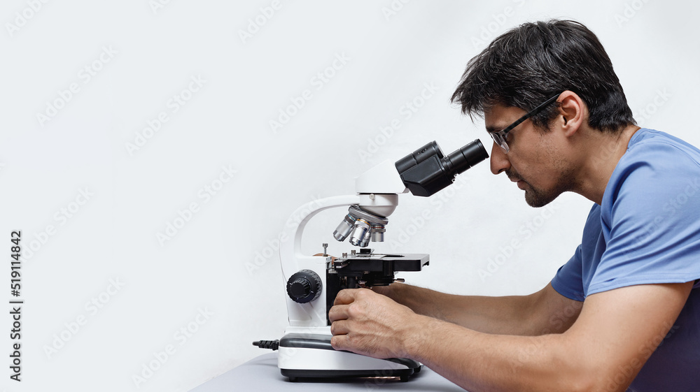 A brunette histologist doctor in a blue medical uniform looks in a ...