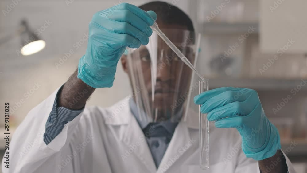 Chest up slowmo of young African American chemist in face shield and ...