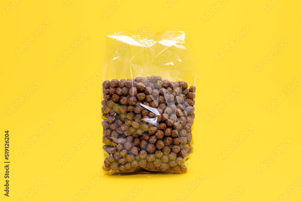 Round chocolate flakes in a transparent package on a yellow background ...