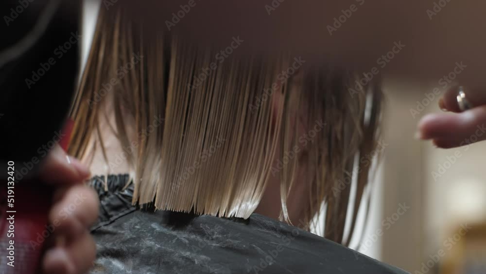 Slow motion of hairdresser cuts with scissors hair of woman in ...