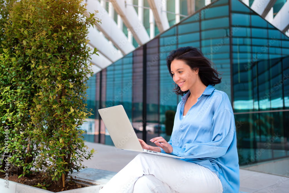 Self employed woman working with laptop sitting outdoor near ...