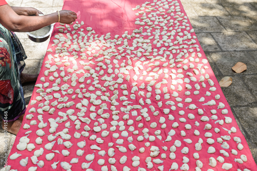 A woman is in the process of making Traditional South Indian snack ...