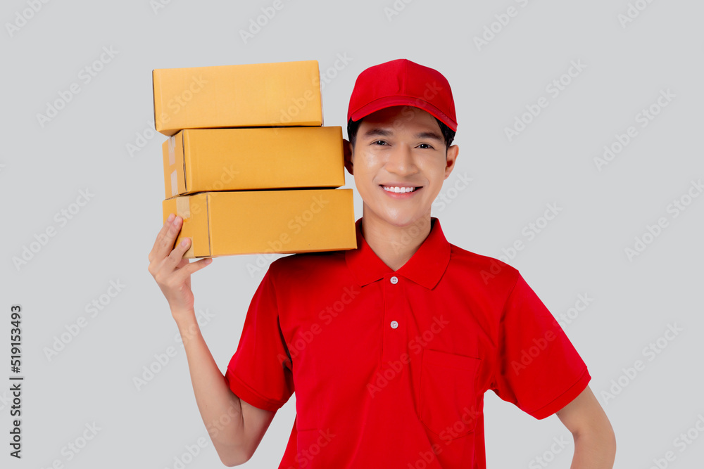 Young asian man in uniform red and cap standing carrying box stack ...