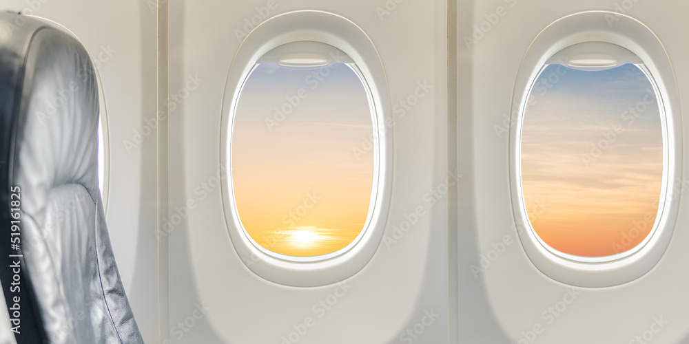Windows and seat inside airplane flying on sunset sky in the morning ...