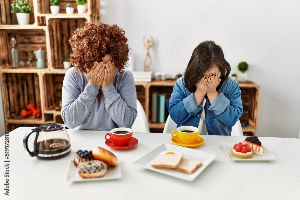 Family of mother and down syndrome daughter sitting at home eating ...