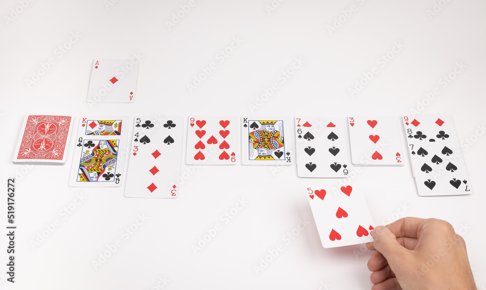 Person playing solitaire on white background with standard playing ...