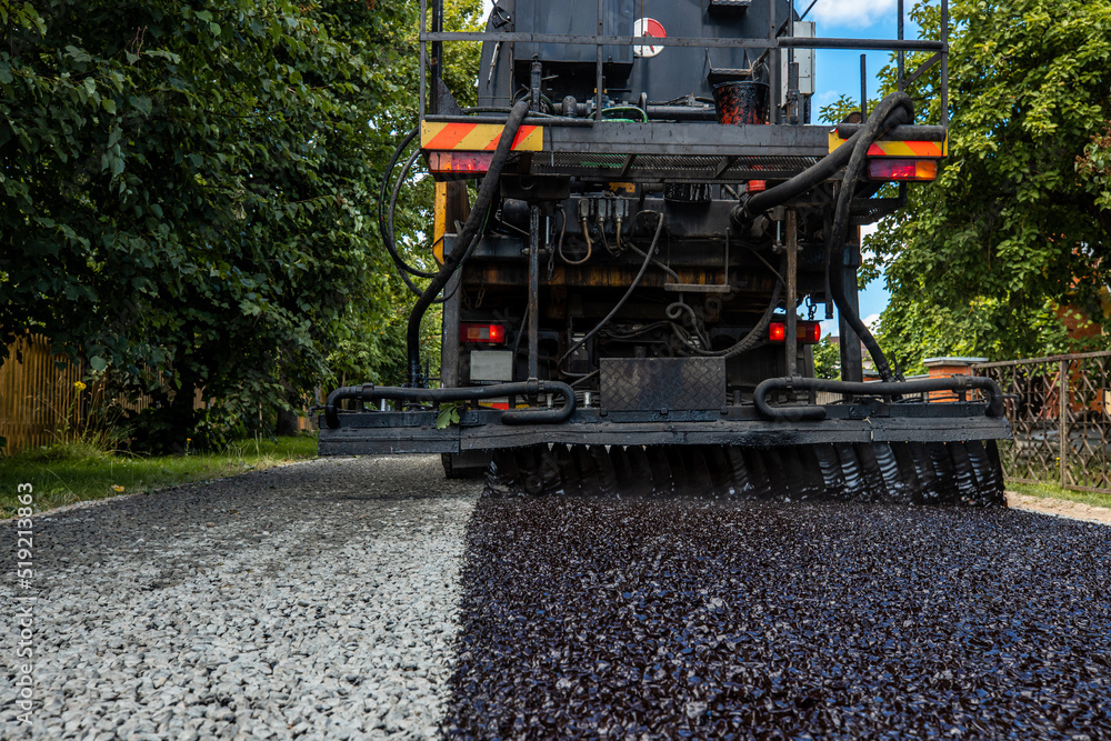 Construction site is laying new asphalt road pavement. Pours liquid ...