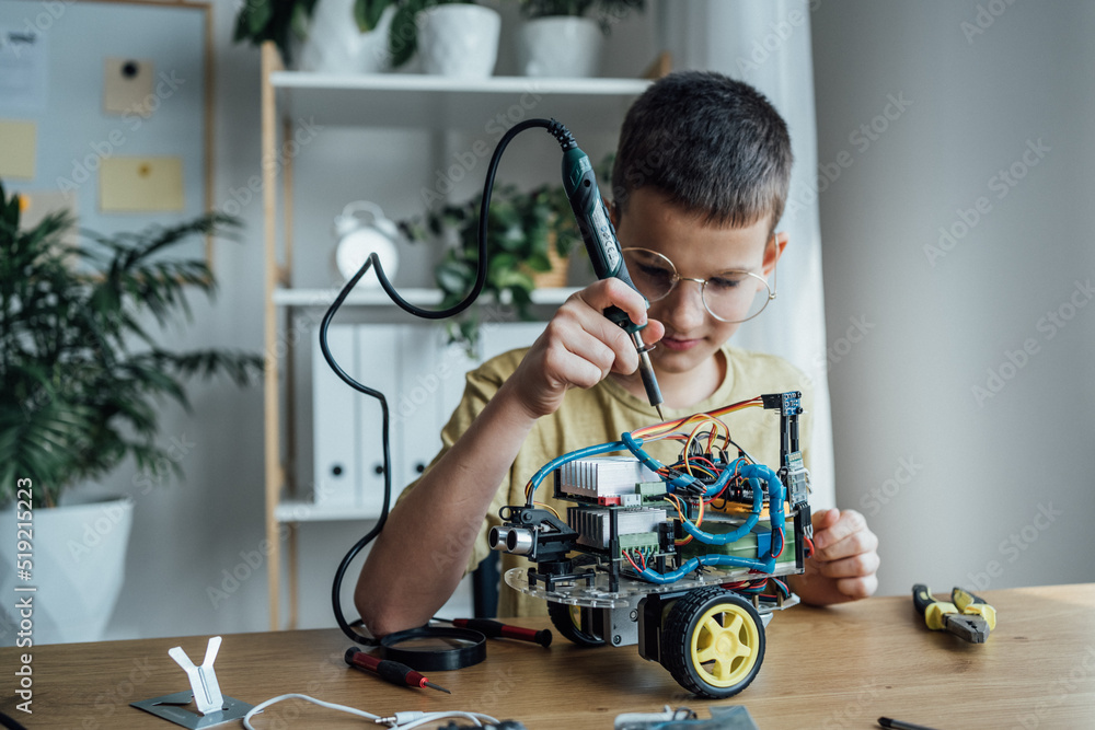 Cute child in casual clothes assemble robot. Kid constructs metal robot ...