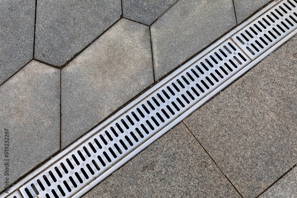 The grid of the rainwater drainage system on the sidewalk made of stone ...