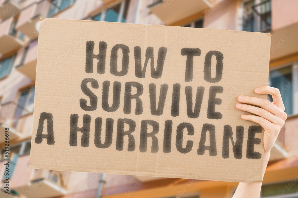 The phrase " How to survive a hurricane " is on a banner in men's hands ...