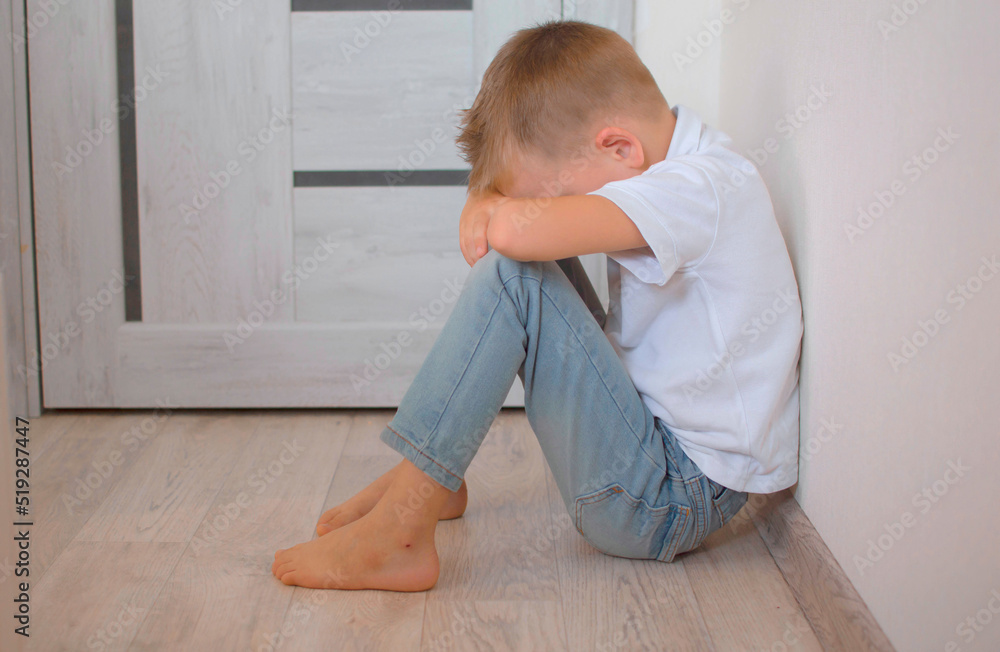 One sad little boy sitting at the door of the house on the floor. Child ...