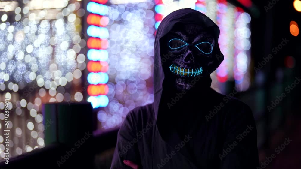 Portrait of a creepy death mask with neon glow dancing in an amusement ...