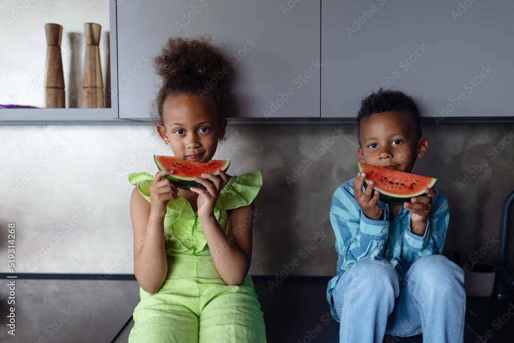 Multiracial kids eating melon in kitchen during hot sunny days. Stock ...