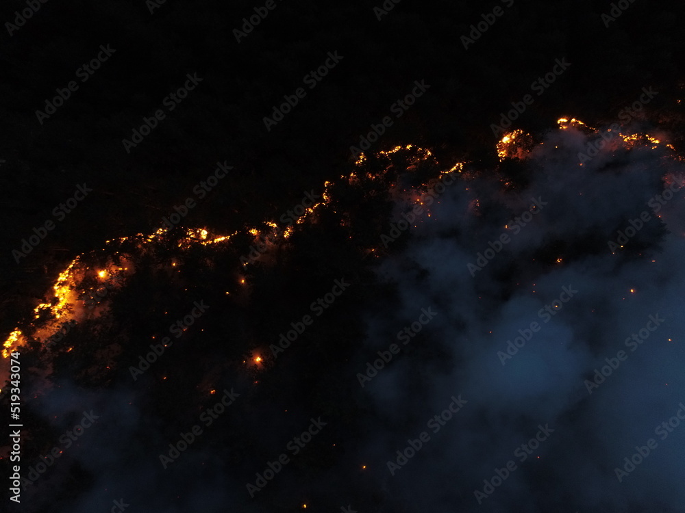 Aerial panoramic view of a forest fire at night, heavy smoke causes air ...