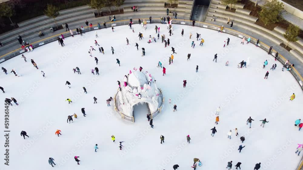 Many people are skating on a white outdoor ice rink in the city on ...