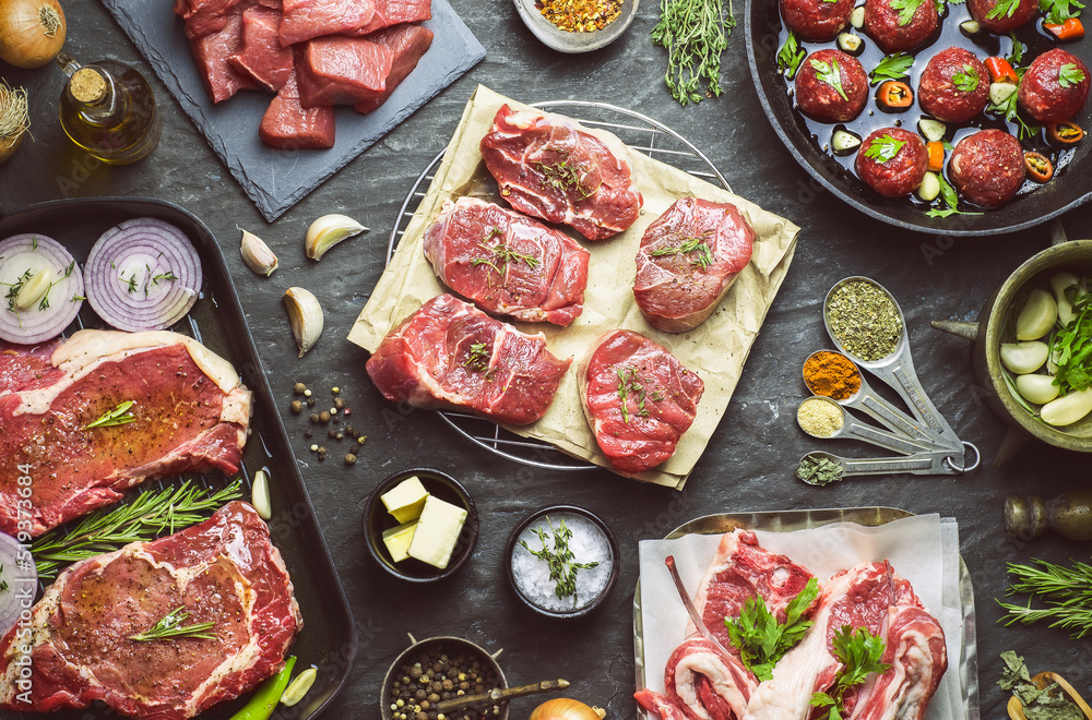 Different types of fresh raw meat sprinkled with seasonings and placed ...