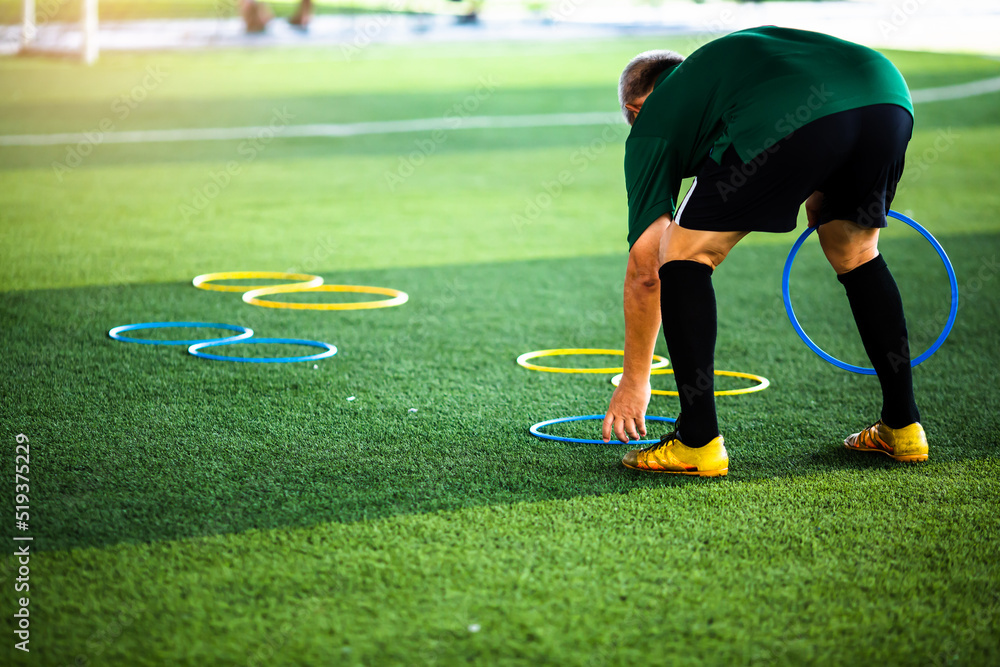 Coach is putting the marker ring for soccer training to run and jump ...