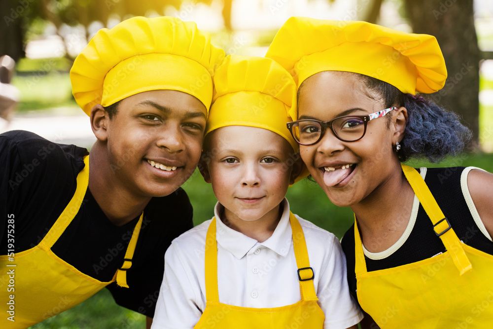 Multinational company of children cooks in yellow uniforms smiling and ...