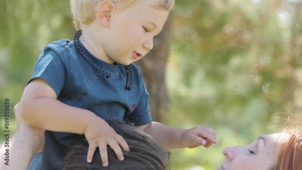 Little boy sitting on the neck of his father and touching his mother ...