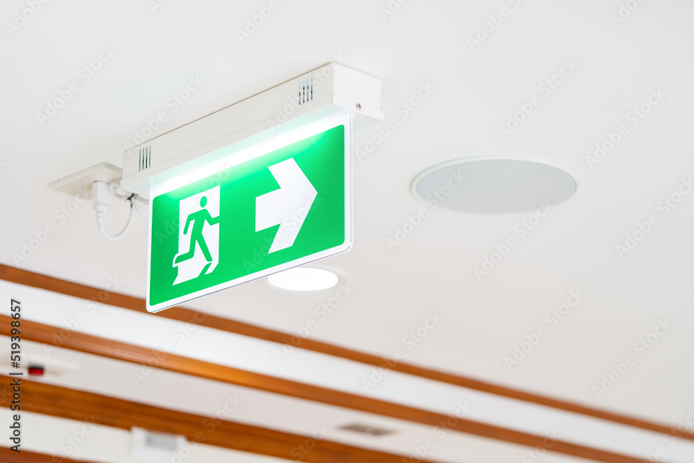 A Arrow light box sign of EMERGENCY FIRE EXIT is hung on the ceiling in ...