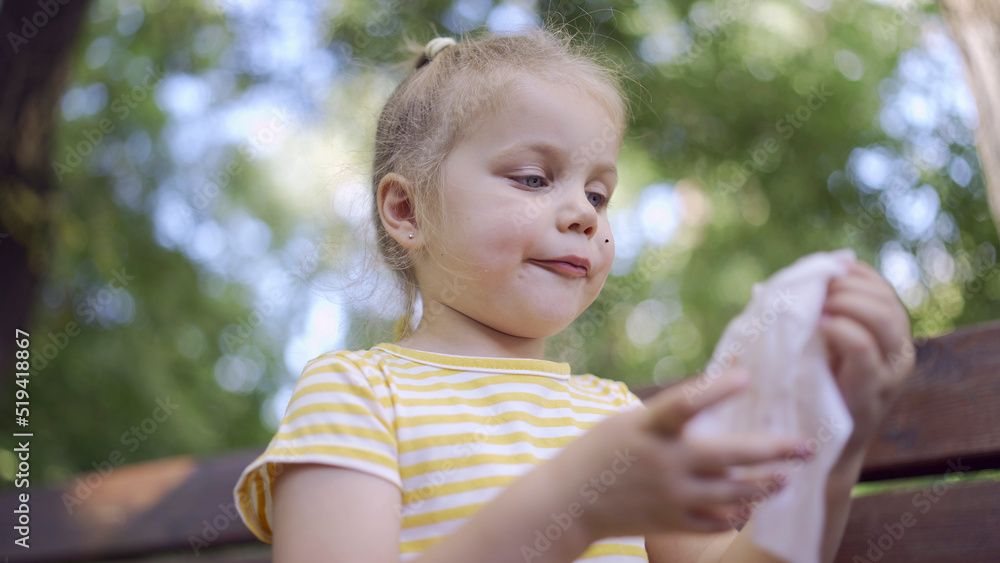Little girl wipes her face with a paper napkin after eating, there is a ...