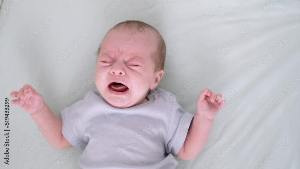 Dissatisfied, crying, upset, sad Newborn baby boy lying in nursery in ...