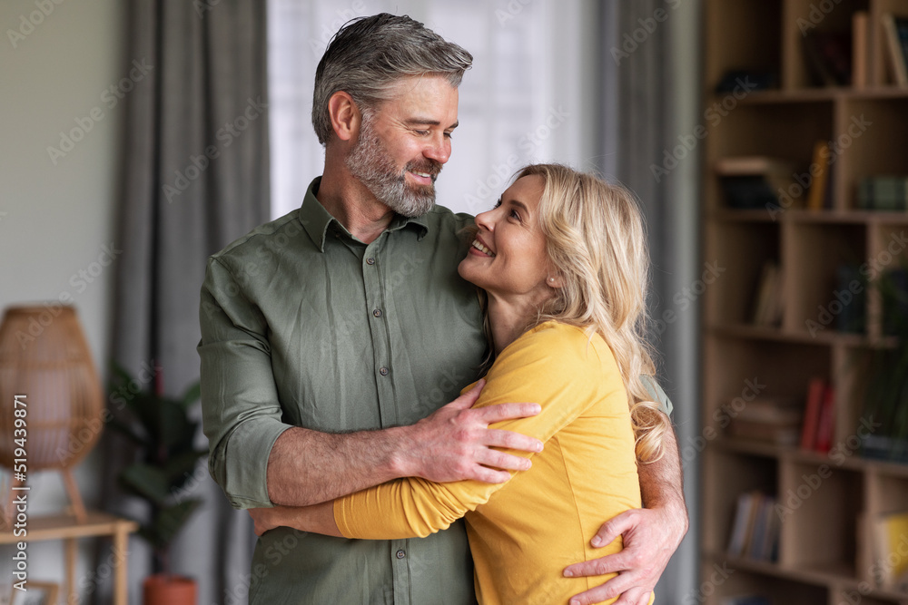 Romantic Middle Aged Couple Embracing At Home And Smiling To Each Other ...