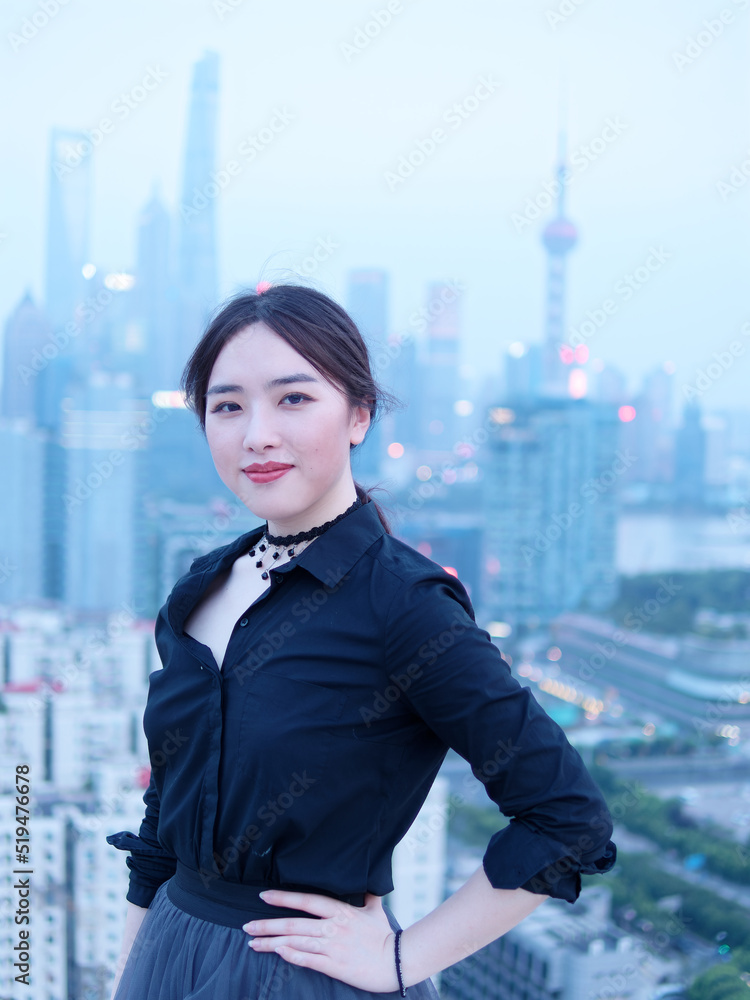 Beautiful young Chinese woman in black posing on top of mansion roof ...