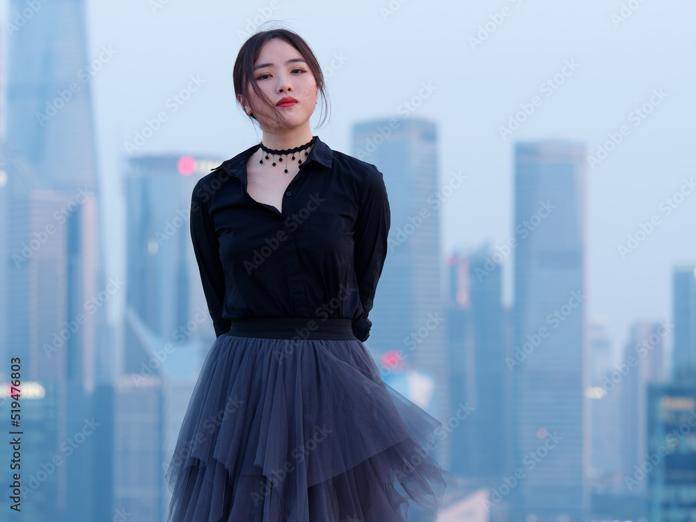 Beautiful young Chinese woman in black posing on top of mansion roof ...
