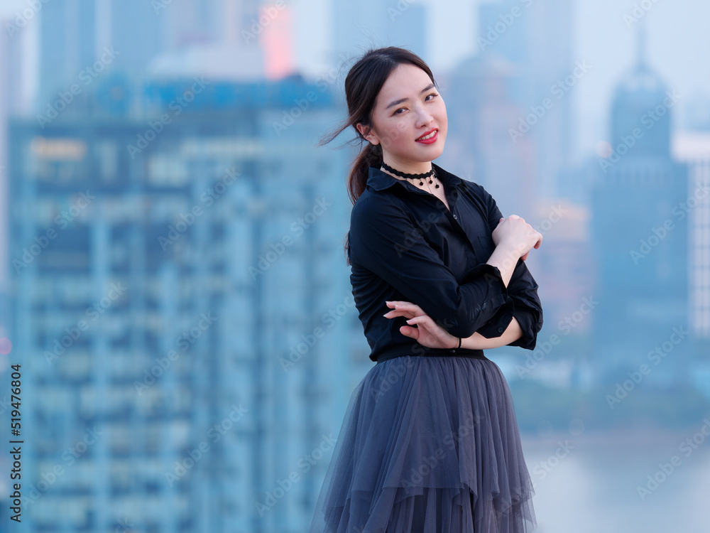 Beautiful young Chinese woman in black posing on top of mansion roof ...