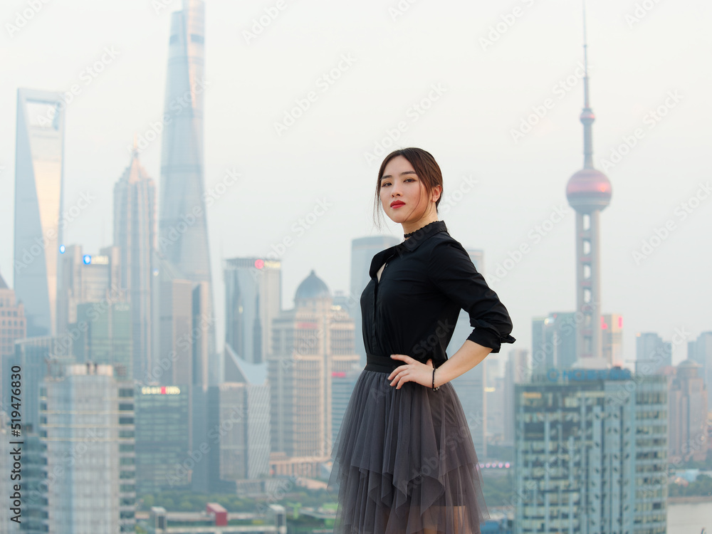Beautiful young Chinese woman in black posing on top of mansion roof ...