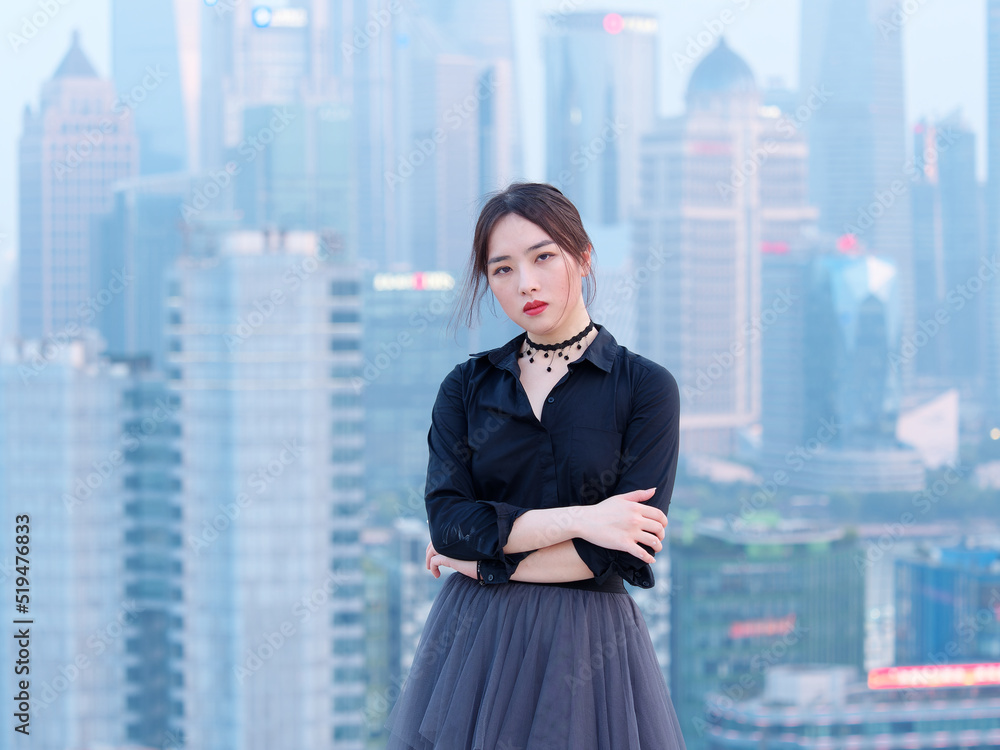 Beautiful young Chinese woman in black posing on top of mansion roof ...