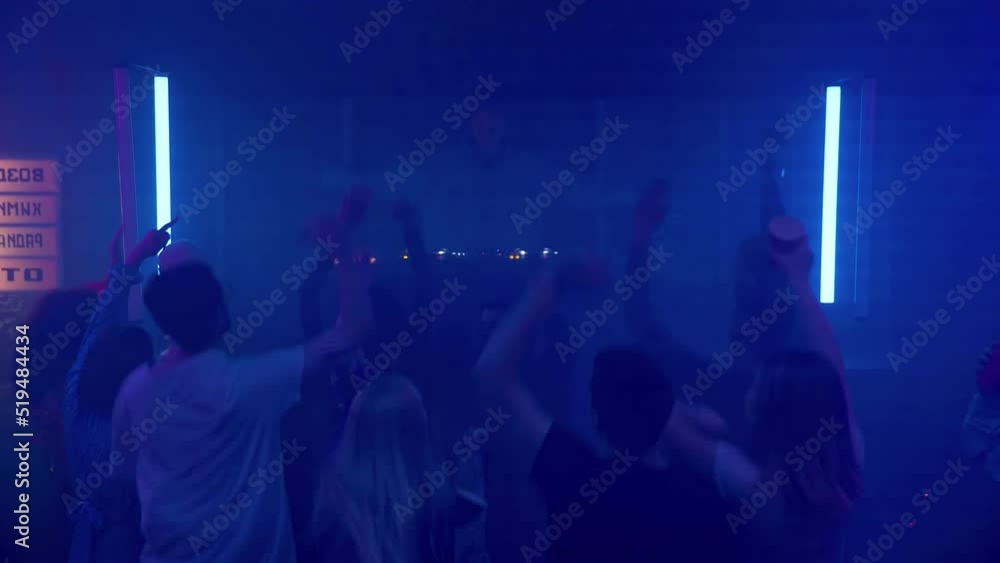 A crowd of people dancing on the dance floor of a nightclub under the ...